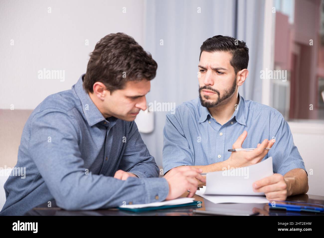 Two serious men with documents at table Stock Photo - Alamy