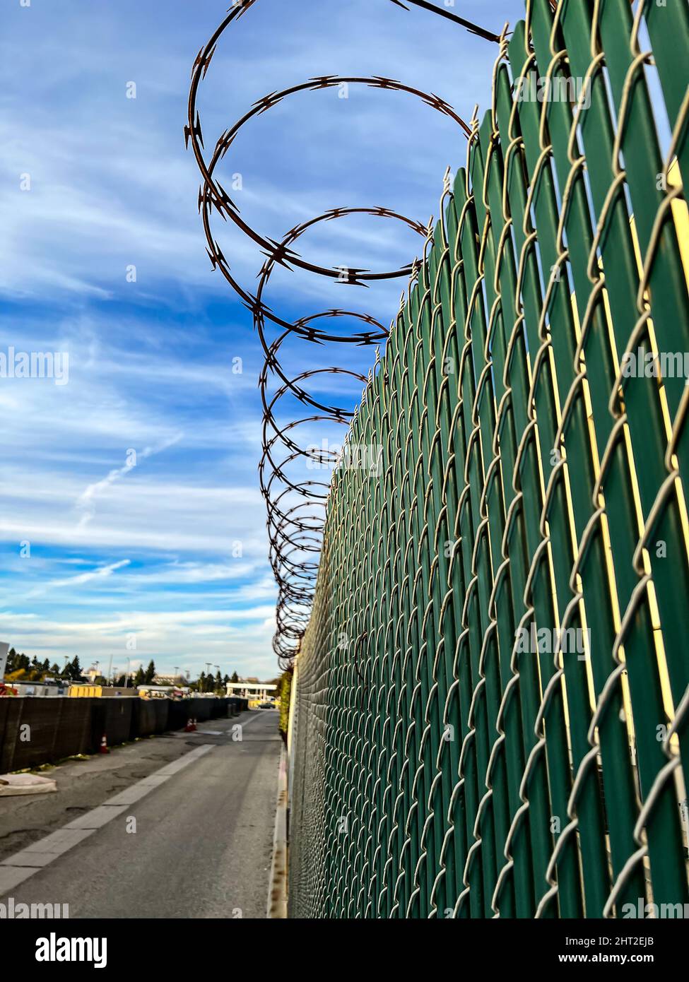 Barbed razor wire on top of slat chainlink fence in a construction zone ...