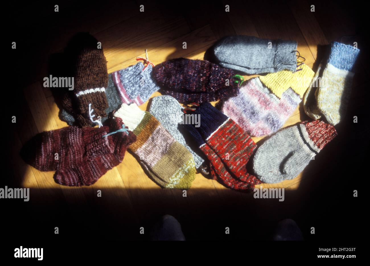 The colorful craft of knitted mittens on a floor is analog. Various ...