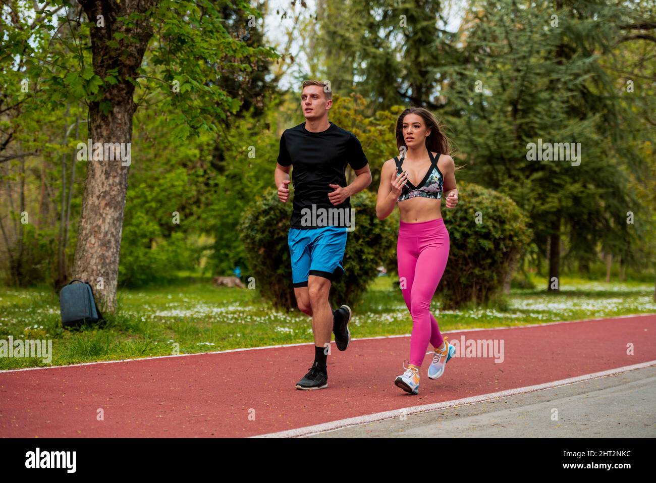 Positive young couple keeping active lifestyle and jogging along city ...