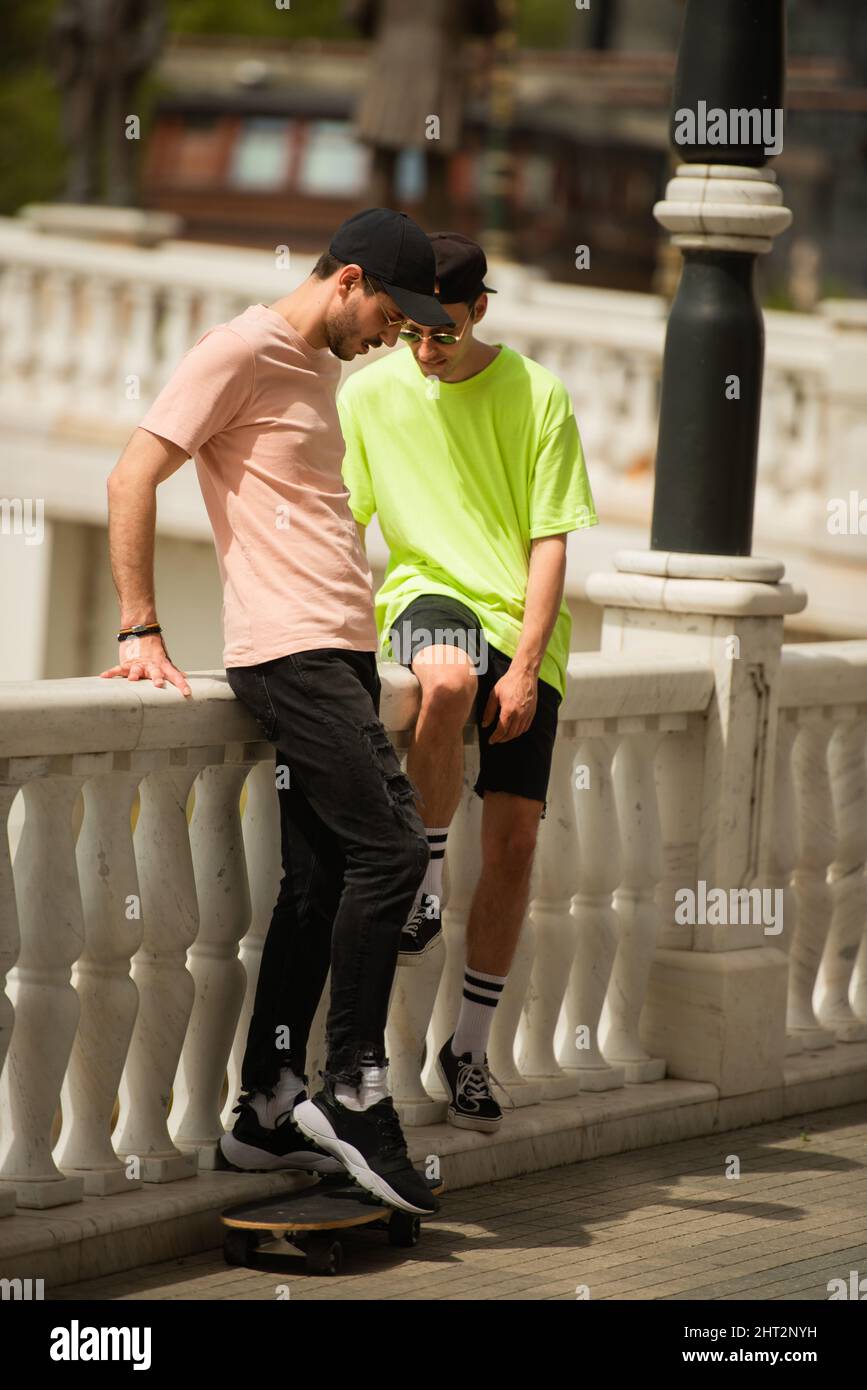 Two friends are talking while one of them is trying to sit on the ...