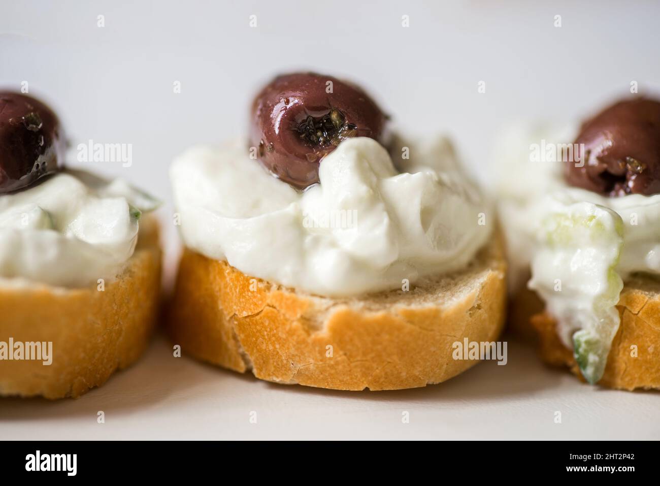 Three small piece of bread with tzatziki spread and olive, closeup ...