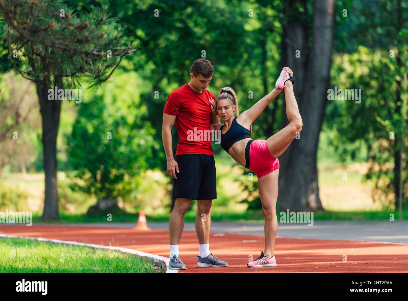 Young male athlete supporting his young female partner while she is ...