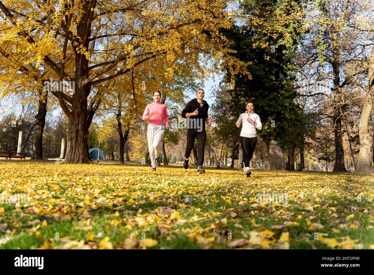 Three amazing and attractive fit friends are running and smiling ...