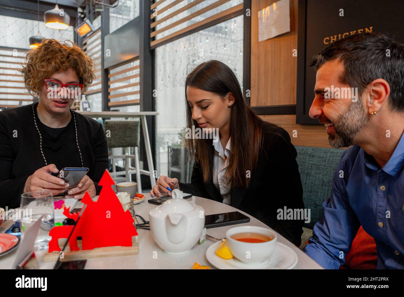 Three amazing business people are smiling and talking while looking at ...