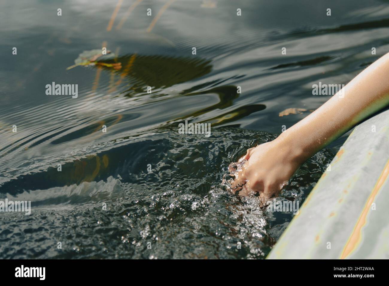 Closeup of a person's hand touching water surface and making waves ...