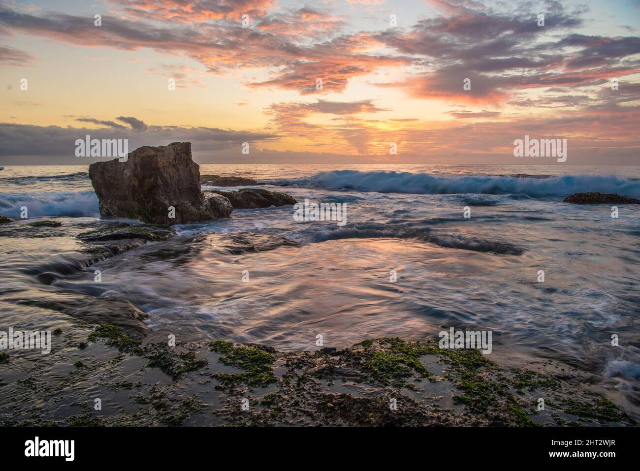 Beautiful view of an orange sunset sky over a beach with water and ...