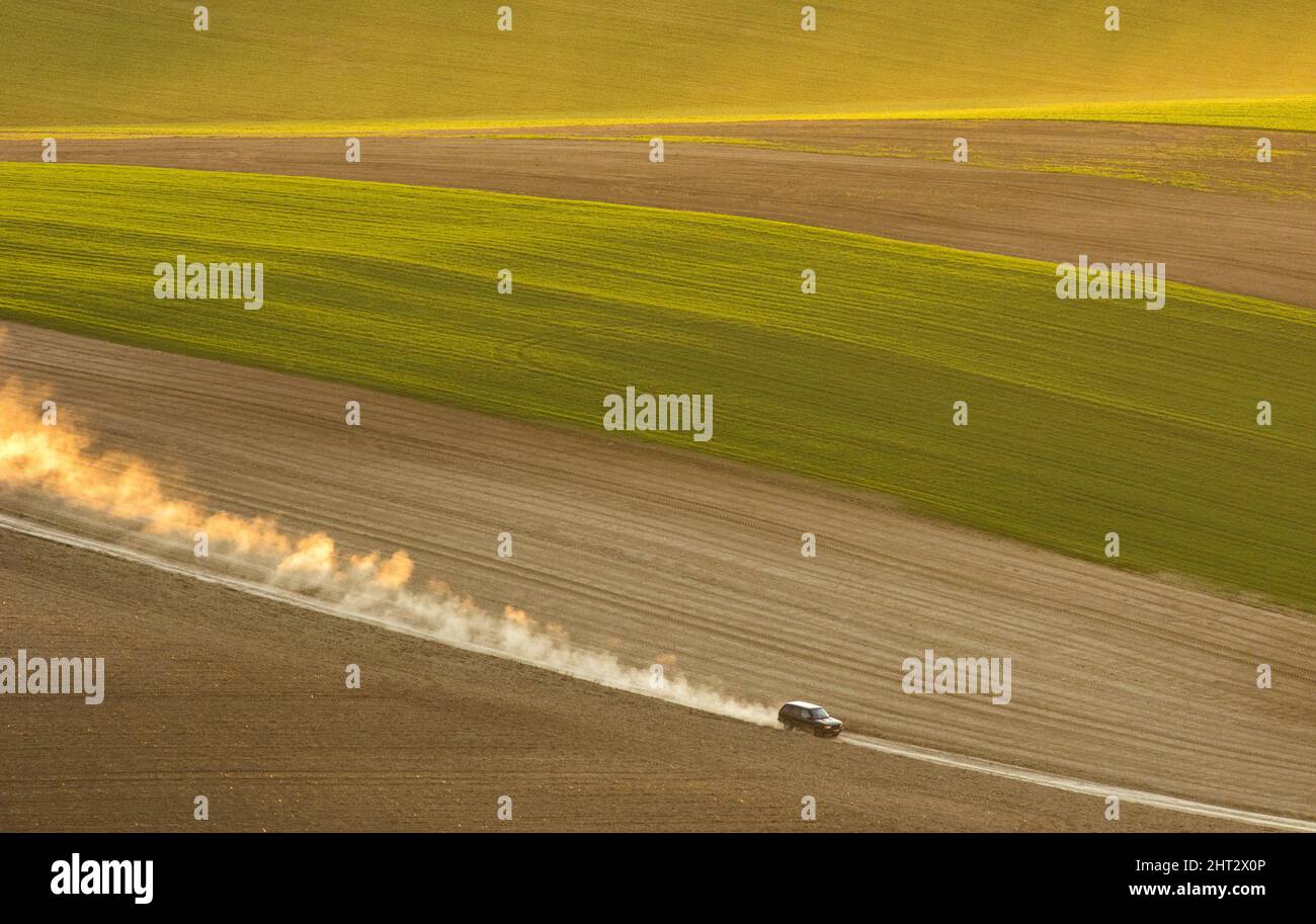 Car blowing up dust while driving down a rural road near a field Stock ...