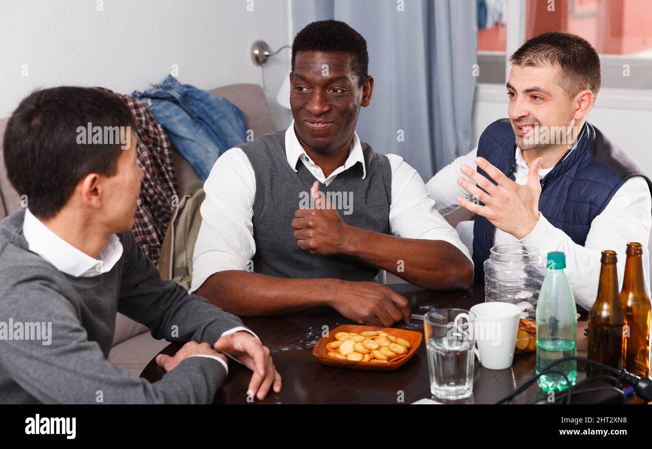 Cheerful men talking at home table Stock Photo - Alamy