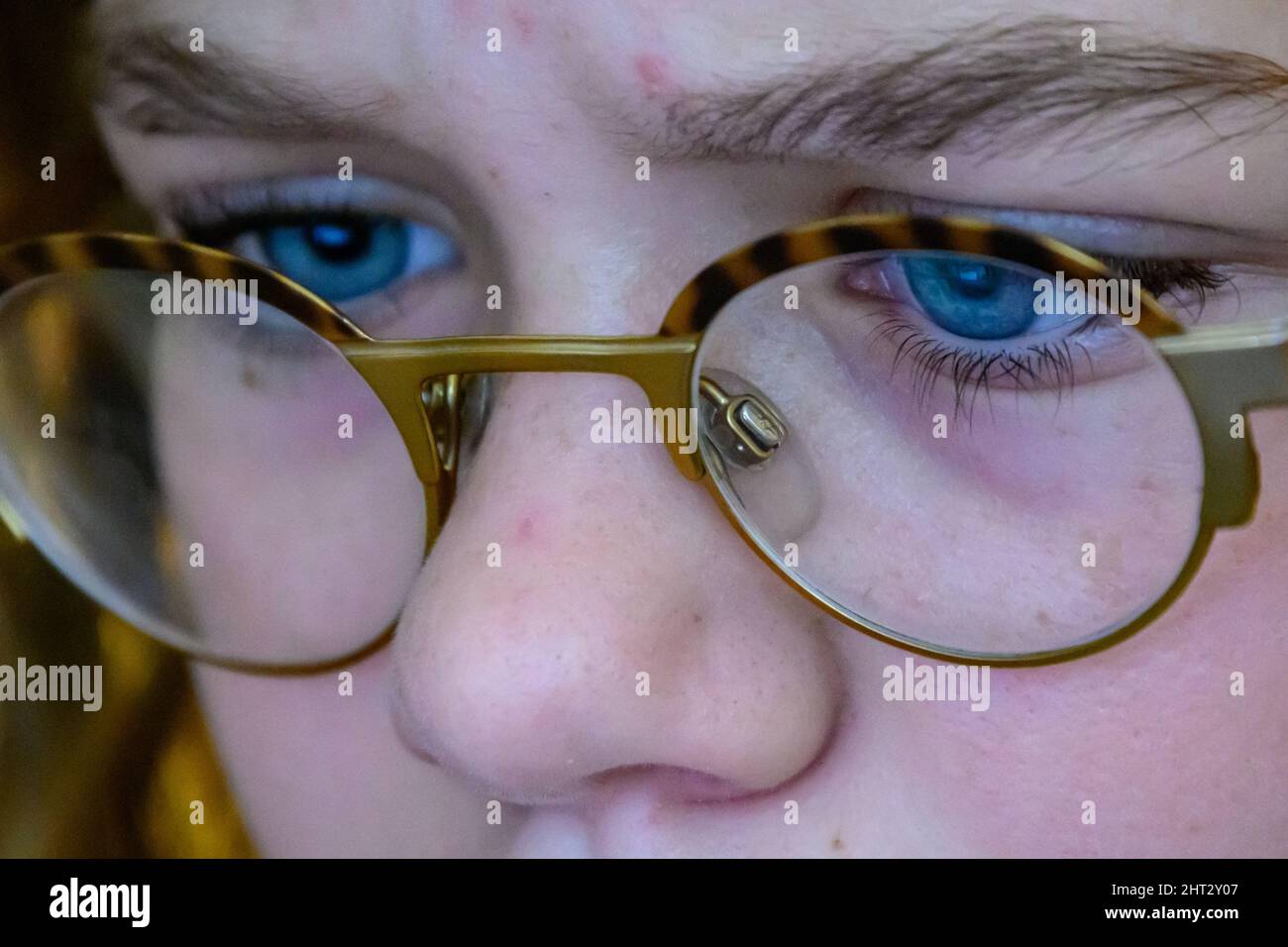 Beautiful blue eyes of a child with a grumpy face wearing optical ...