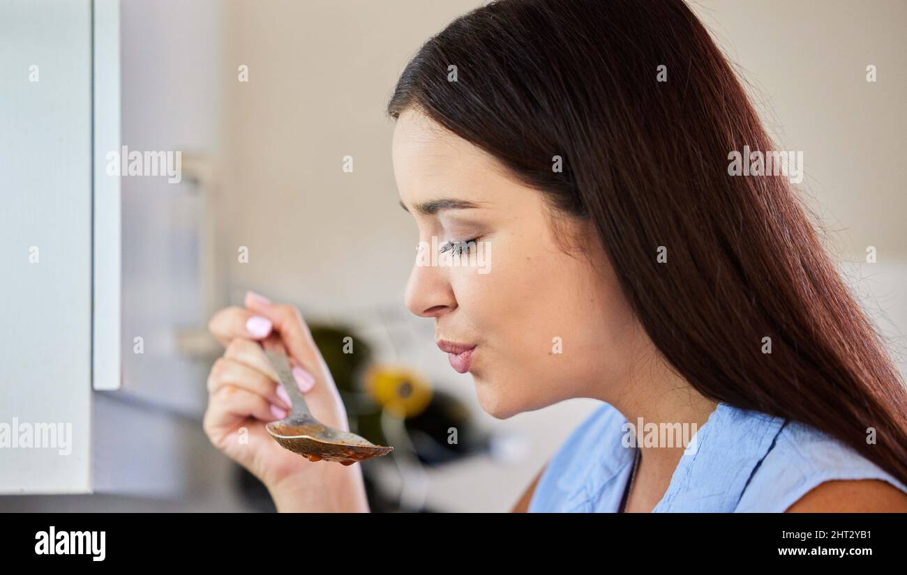 My kitchen is my favourite restaurant. Shot of a young woman tasting ...