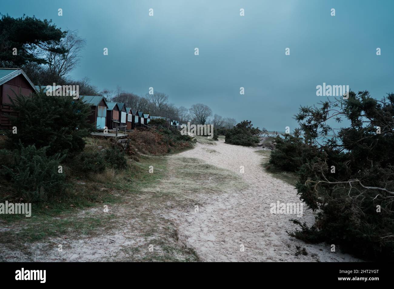 Eerie scenery of a sand pathway by small wooden beach houses on a ...