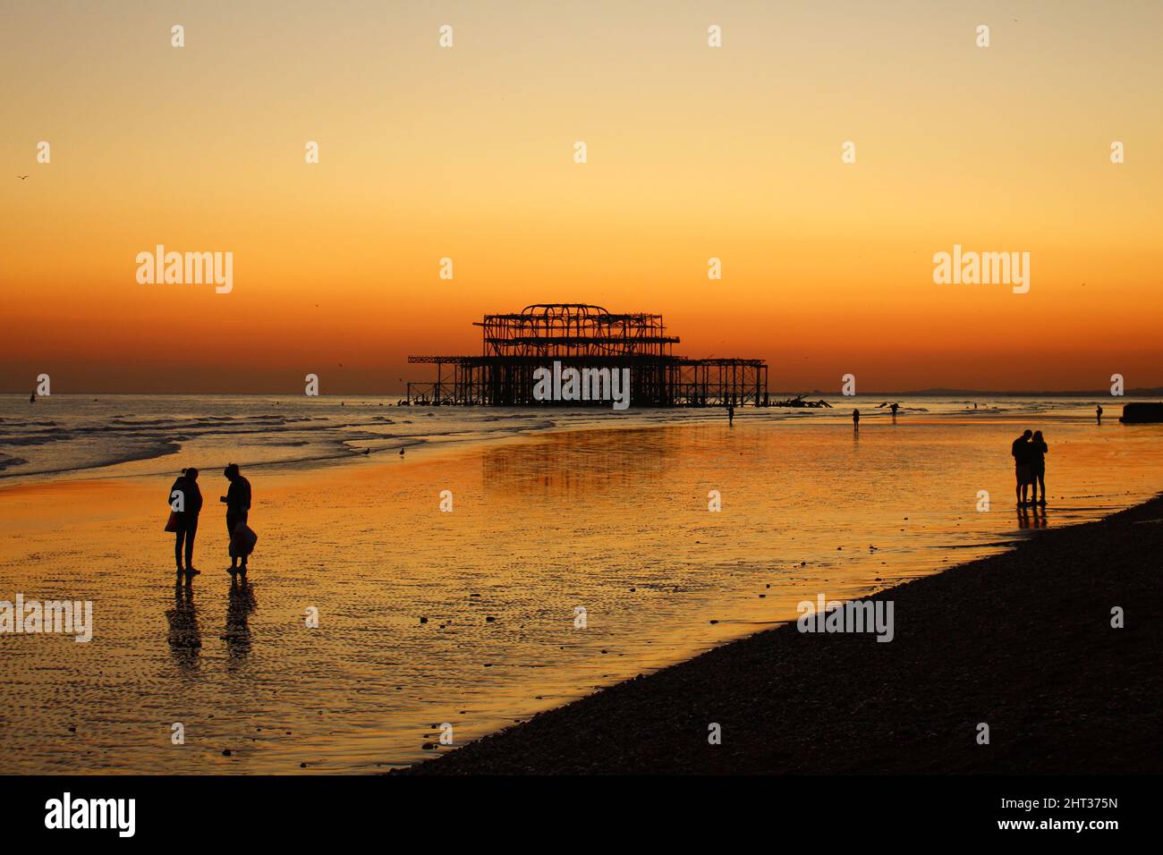 Low tide sunset view of Brighton's derelict west pier with silhouettes ...