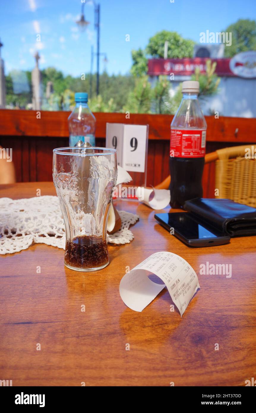 Glass with Coca Cola beverage and a bill on a wooden table of a ...