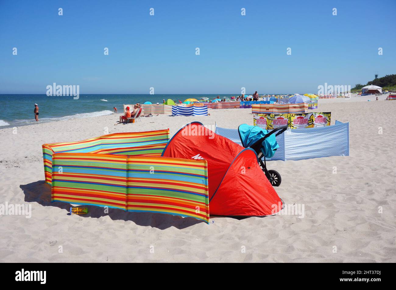 Windbreakers and tents on the sand close by the water at a beach Stock ...