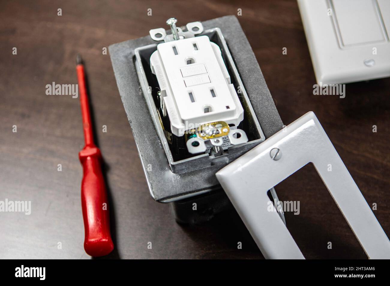 A tested electrical outlet lies on the table before being installed in ...