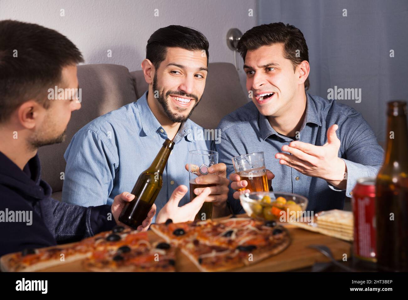 Three men talking and laughing at home Stock Photo - Alamy
