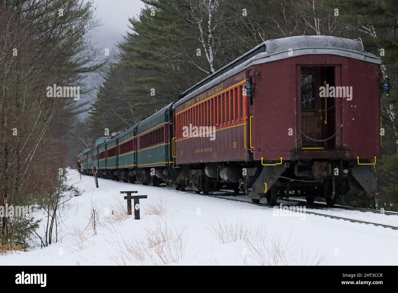 Dark colored passenger train on a snowy railroad in Bartlett, USA Stock ...