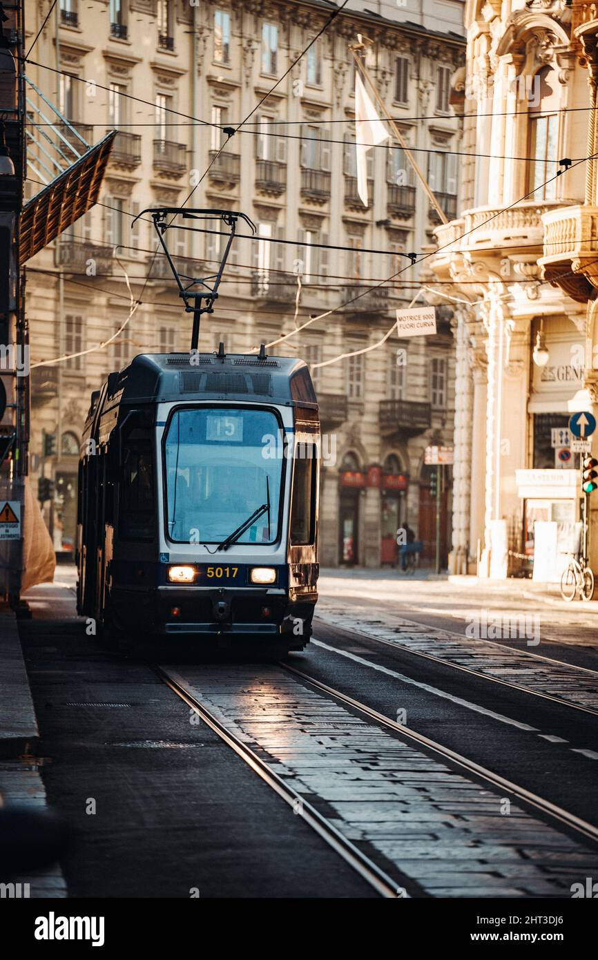 Vertical shot of a modern tram passing by the narrow street with ...