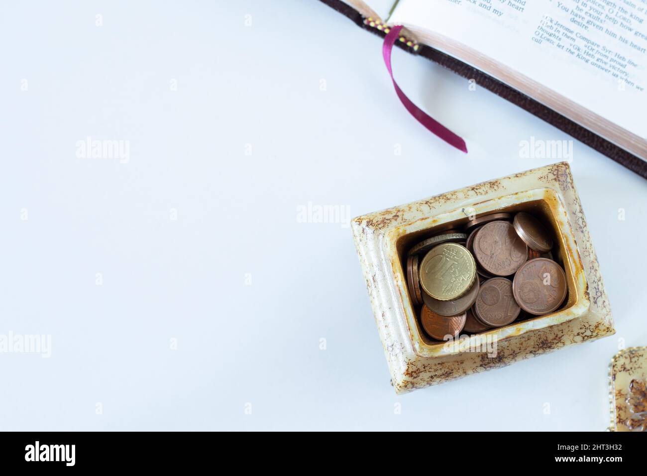 Coins in a golden box with open Holy Bible Book on white background ...