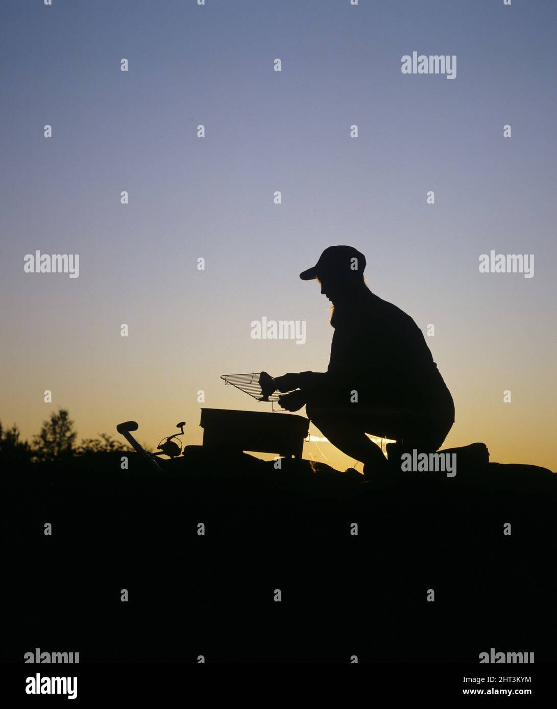 Woman smoking fish in sunset Stock Photo - Alamy