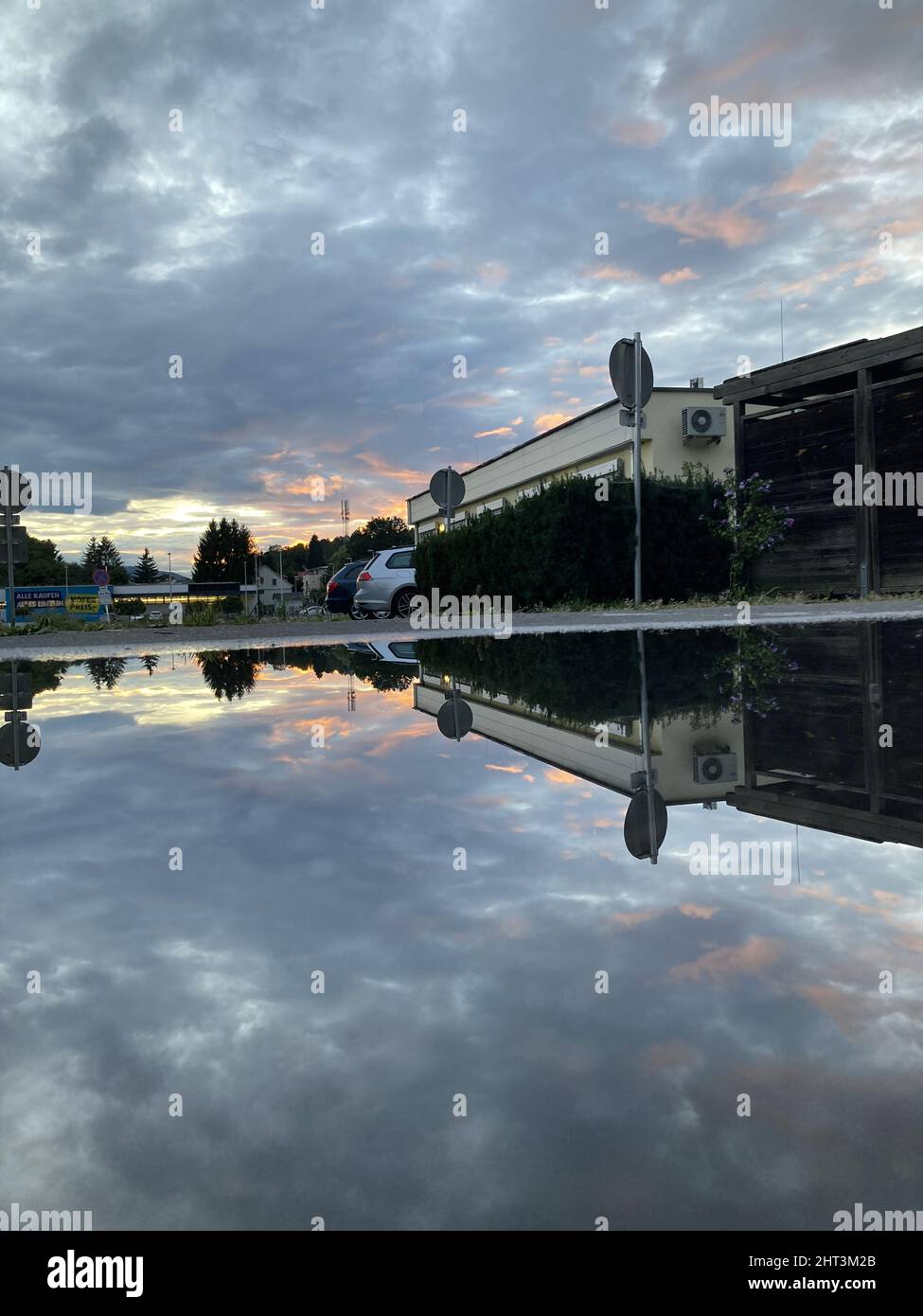 Vertical shot of the water reflection of building, trees and cars with ...