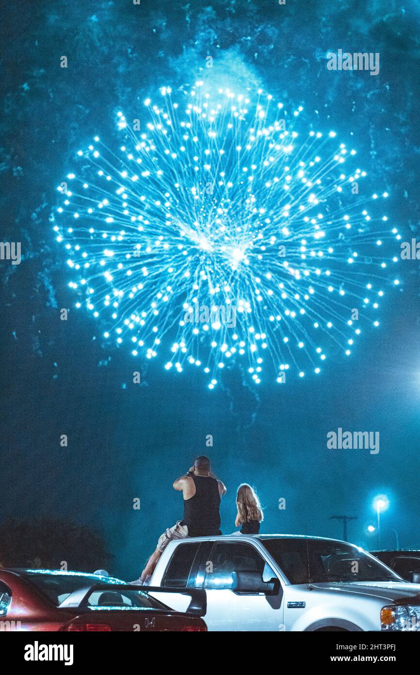 Vertical shot of a father and his daughter sitting on their car and ...
