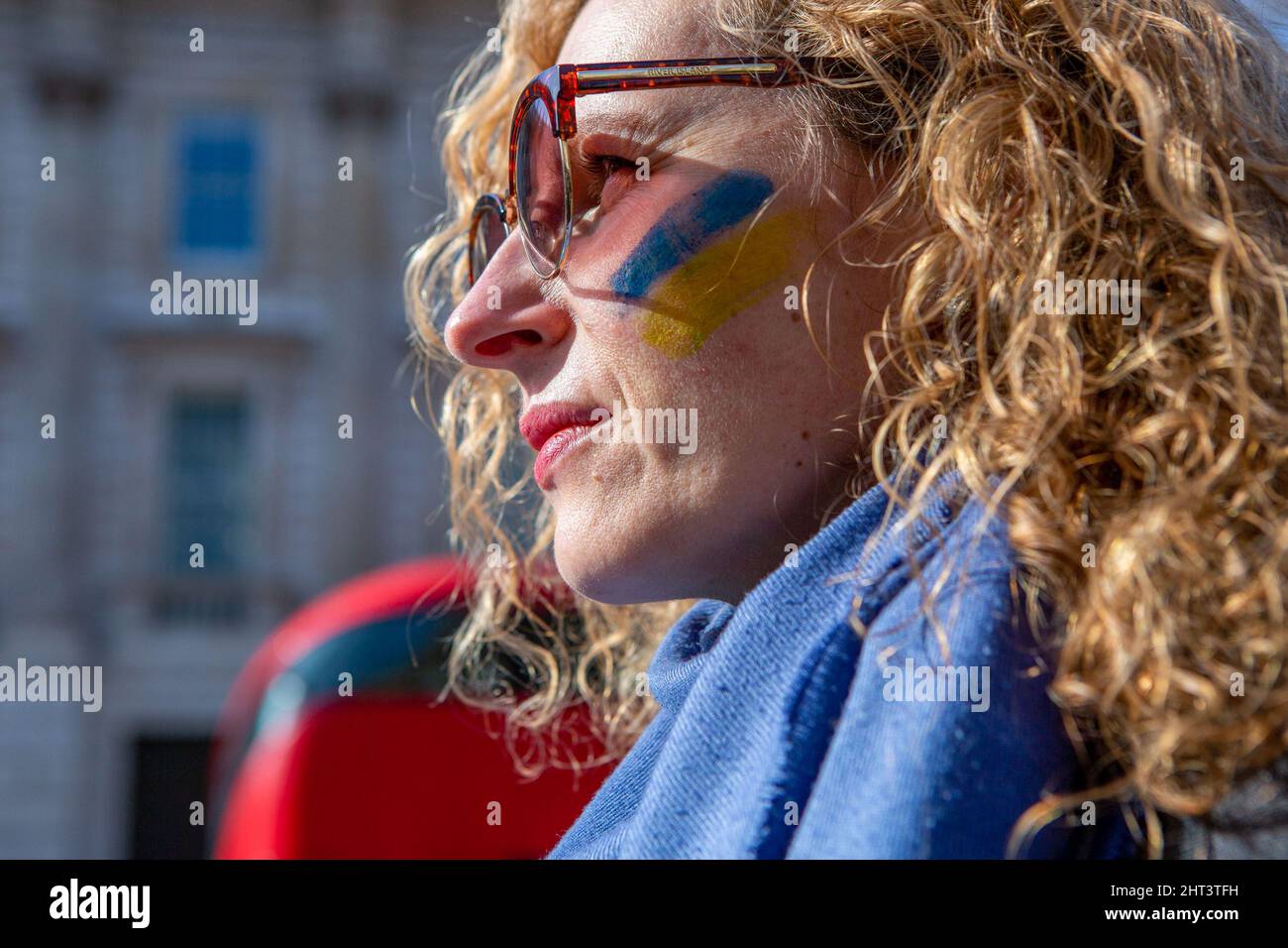 London, UK. 26th Feb, 2022. A Protester has her face painted in yellow ...