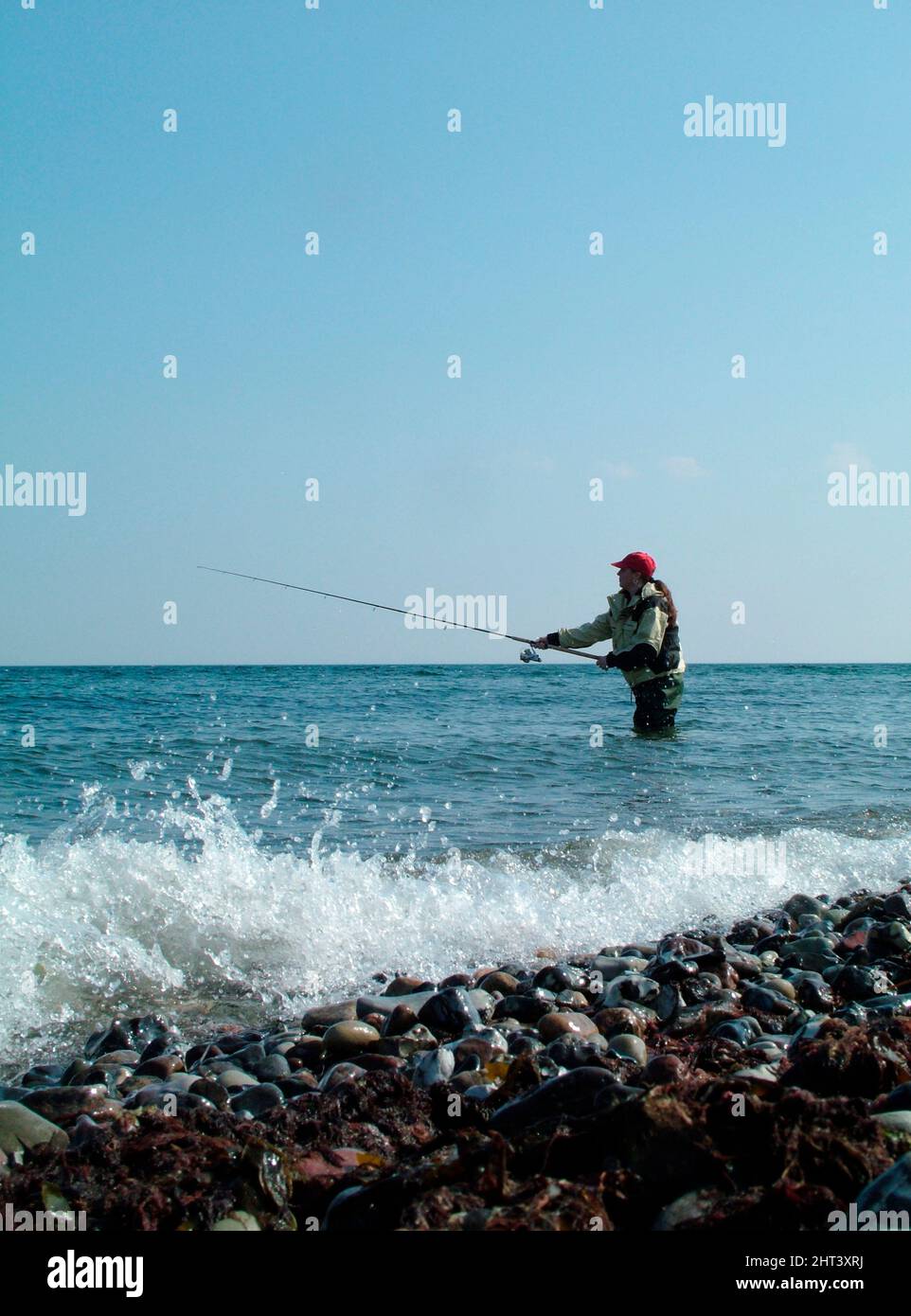 Woman fishing on the coast among waves Stock Photo - Alamy