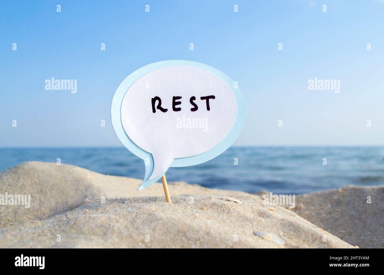 Empty blue white blank speech bubble on wooden stick on sandy sea beach ...