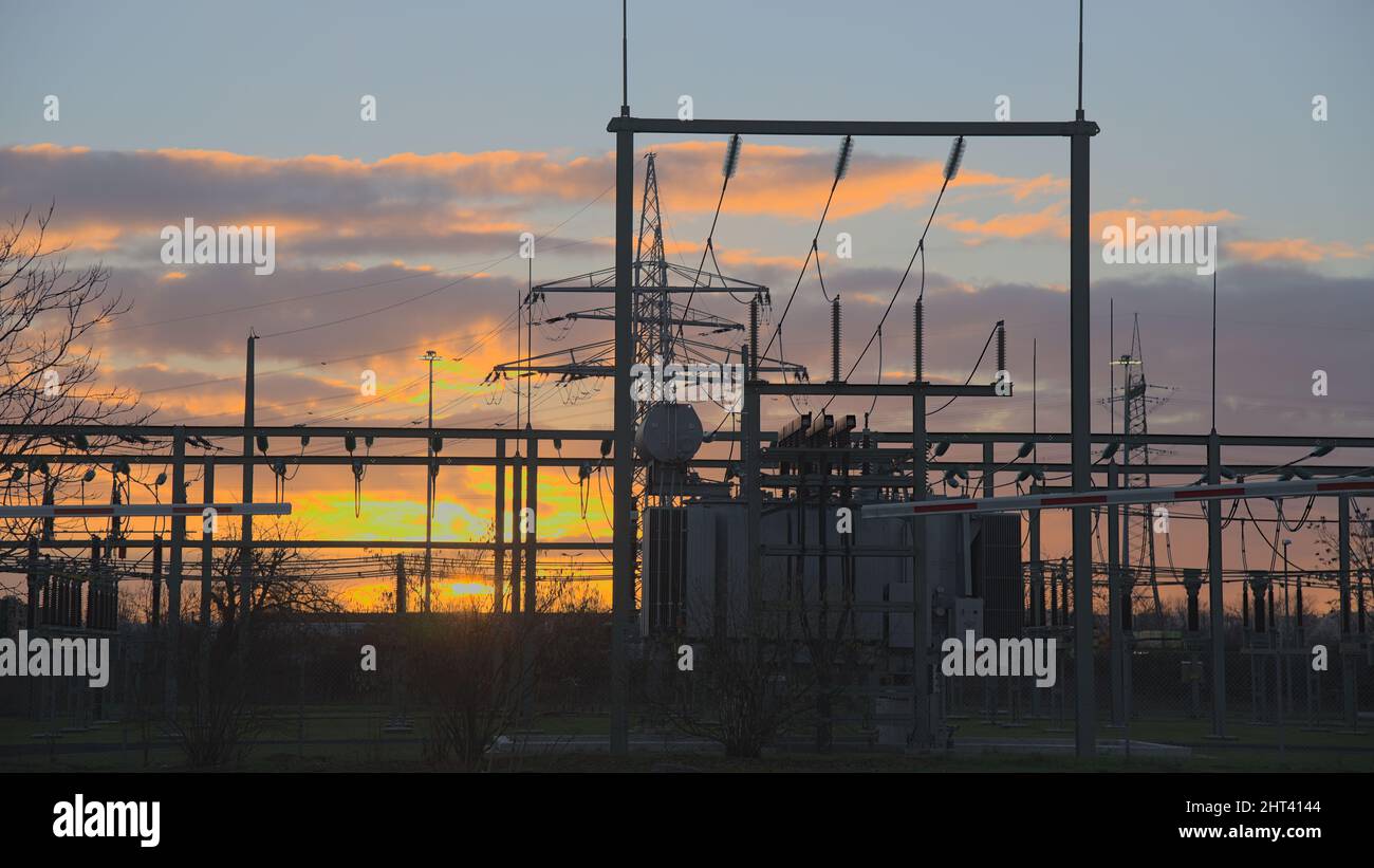 Electrical substation and pylons silhouetted by orange sunset Stock ...