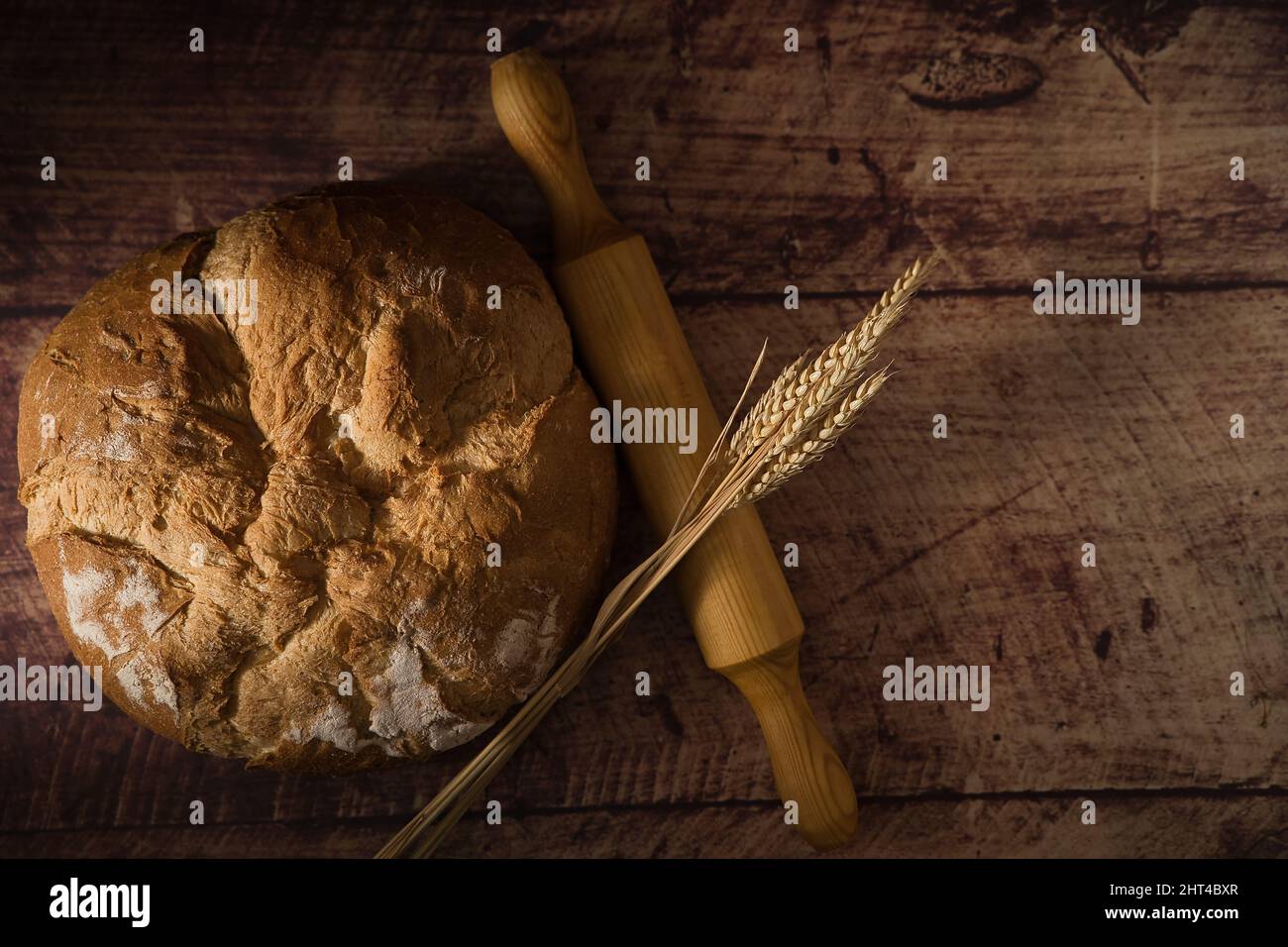 A pan casero artisan bread with a rolling pin and wheat plants on a ...