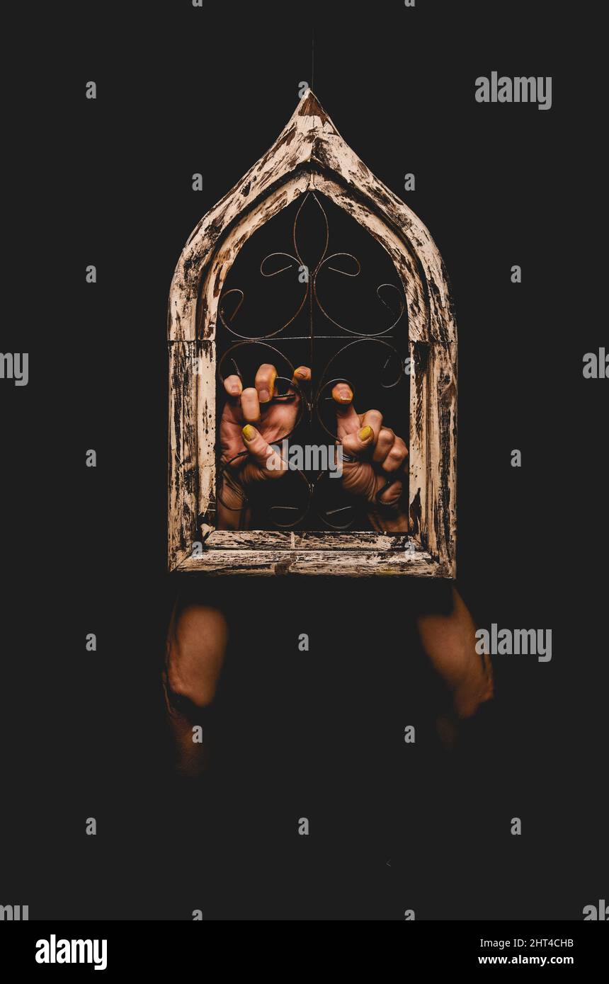 Vertical shot of dramatic hands holding on a window isolated on black ...