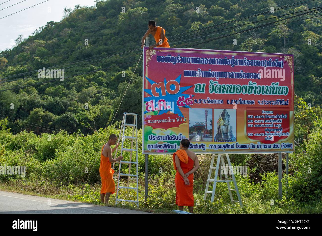 Buddhist monks putting up a poster in the countryside outside Hua Hin ...
