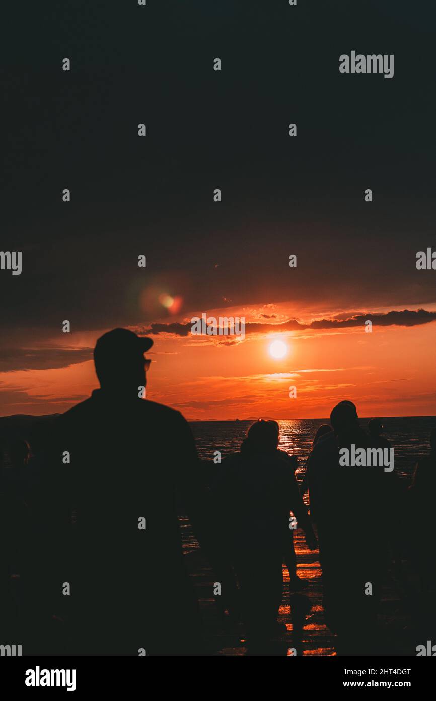Group of people watching sunset Stock Photo - Alamy