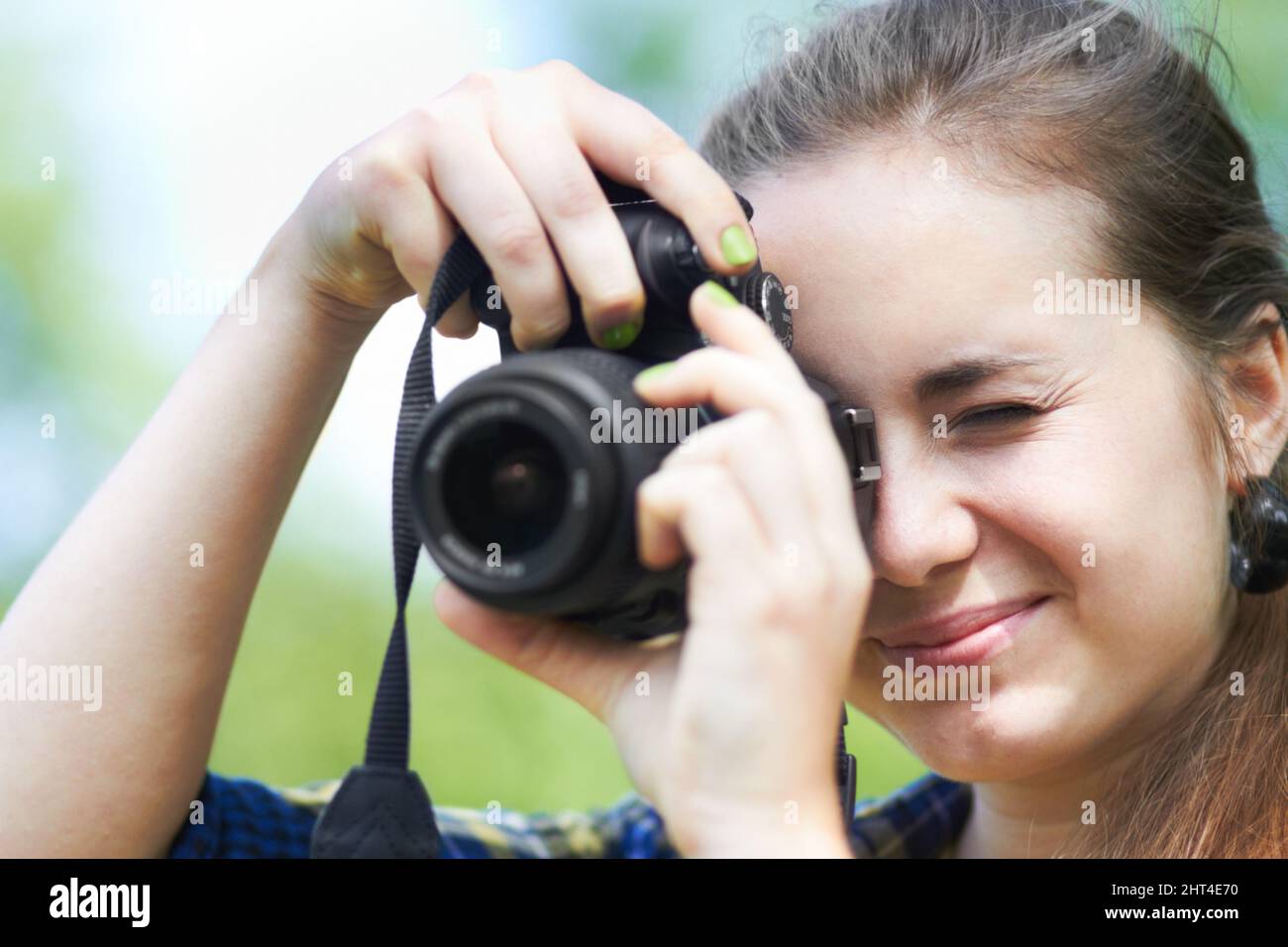 Zooming in to get a good shot. A beautiful young woman taking a picture ...