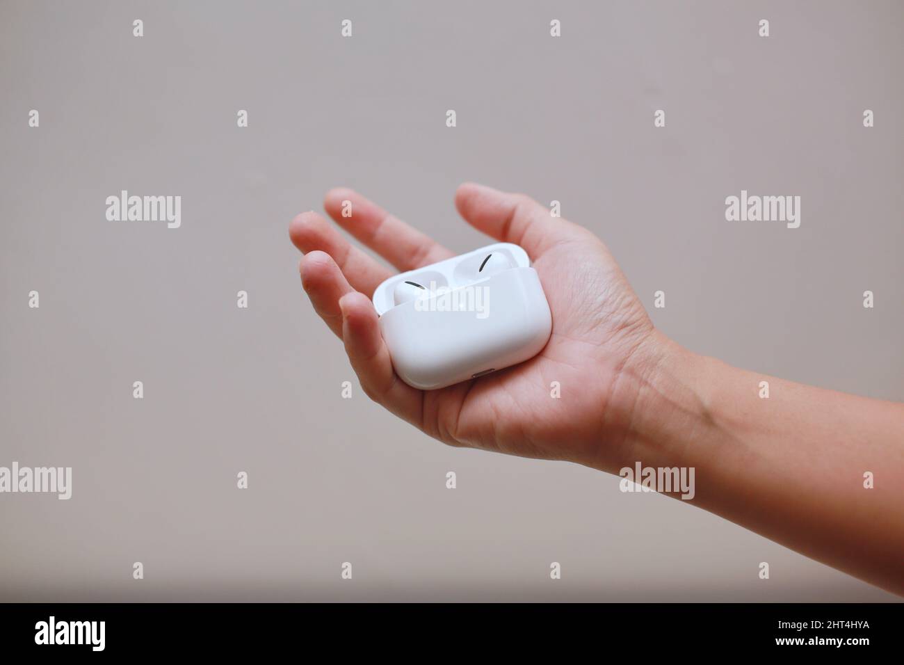 Hand holding Apple pro-Airpod case on a creme wall background Stock ...