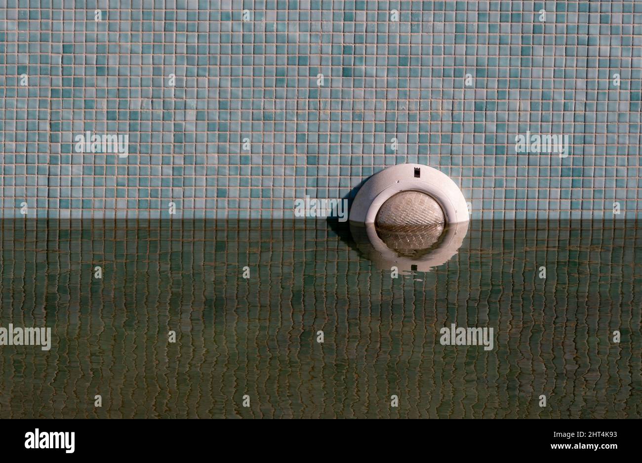Closeup of a tile pattern and the water filter of a pool which is half ...