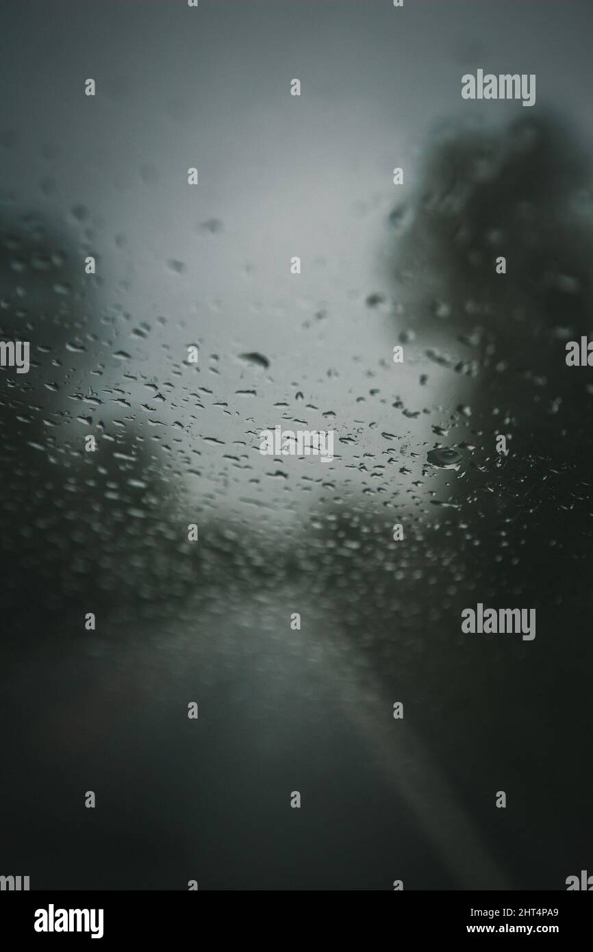 Closeup shot of raindrops on a car window on a gloomy day on the road ...