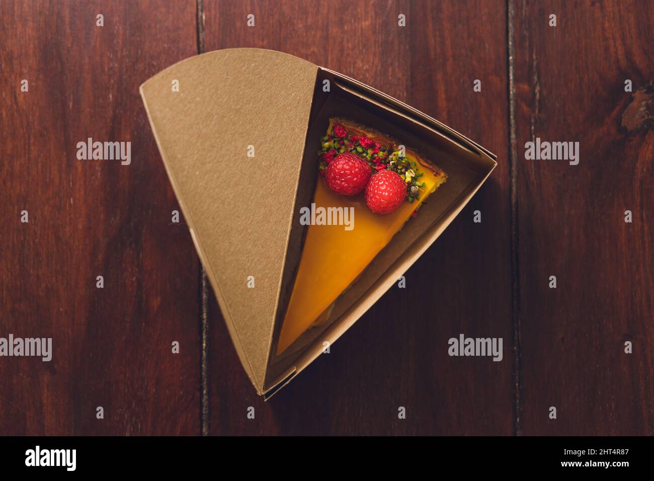 Top view of a mango cheesecake with raspberries in a triangular cake ...