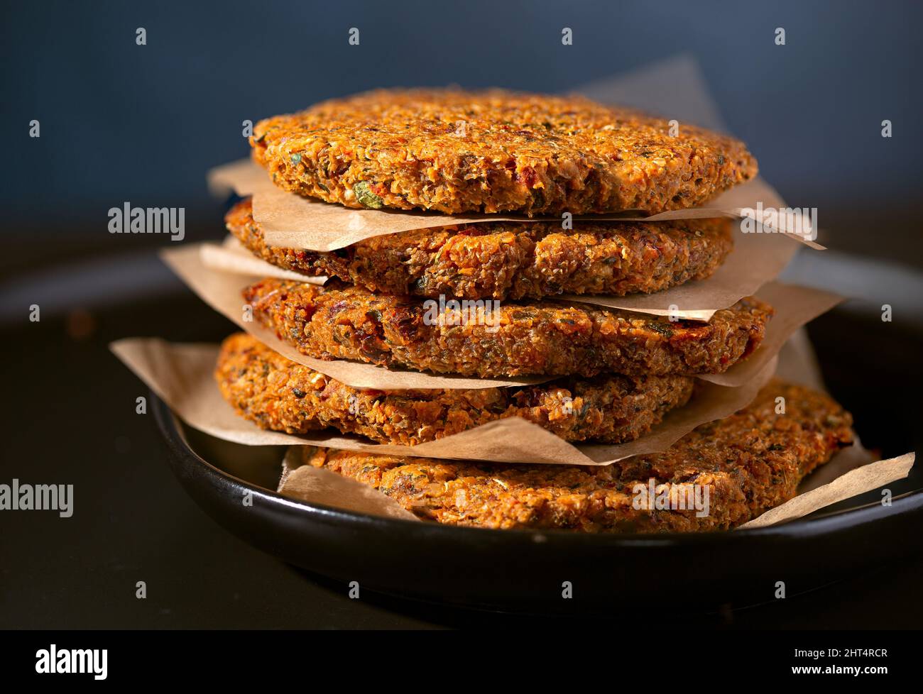 Stack of homemade veggie burger patties separated by parchment paper ...