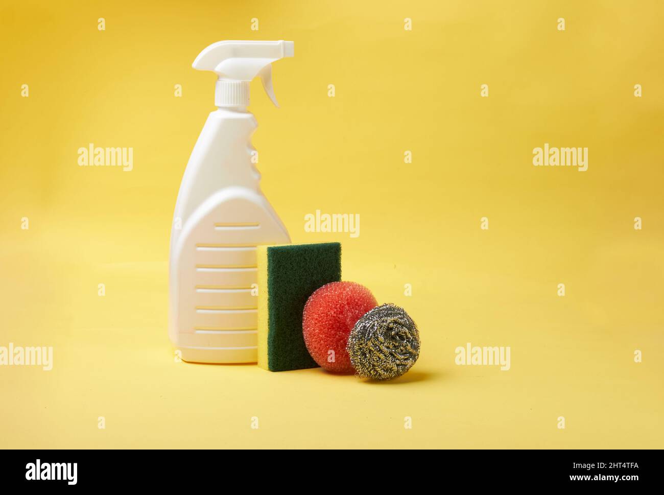 Bottle of cleaning fluid and different sponges isolated on a yellow ...