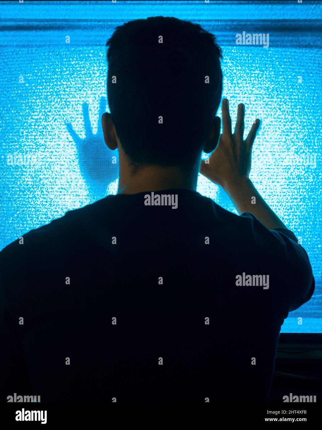 Portrait of the back of a male with his hand on a TV screen with the ...