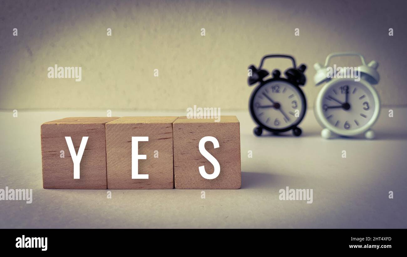 Text on wooden blocks - Yes. With blurred alarm clocks background ...