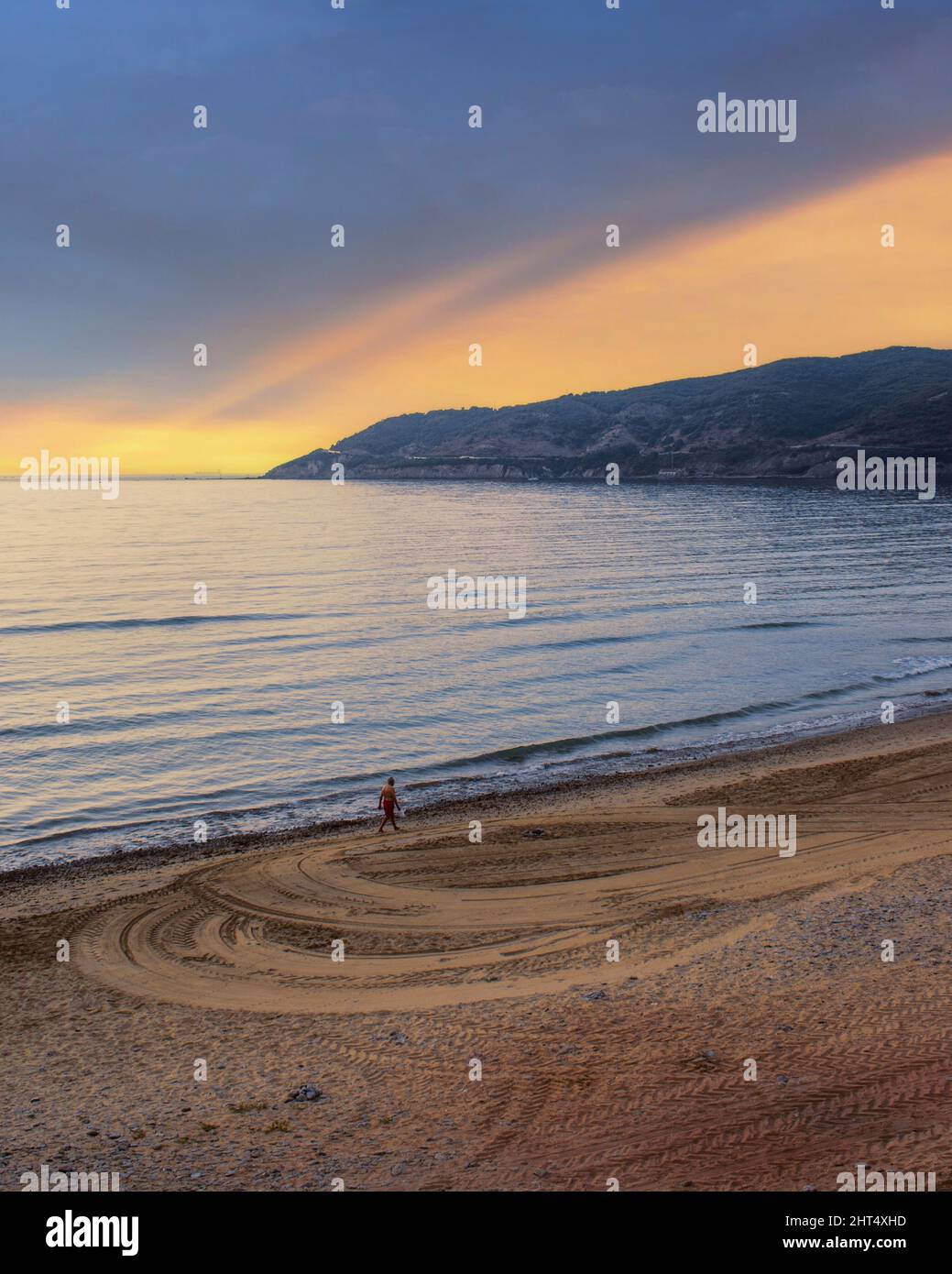 Scenic portrait of a beach with a person walking along the seashore ...