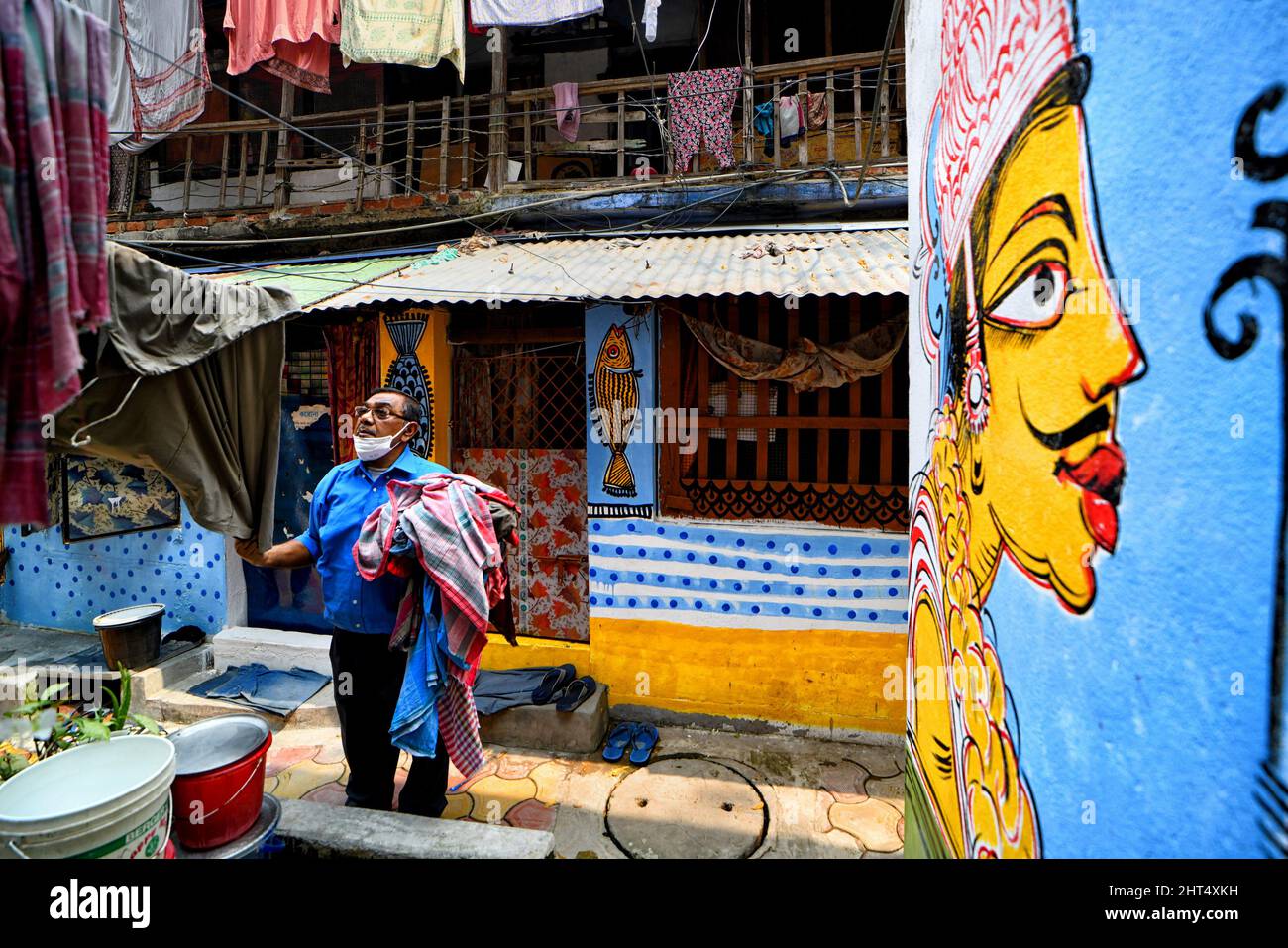 A man seen in a colorful slum surroundings with beautiful wall graffiti ...