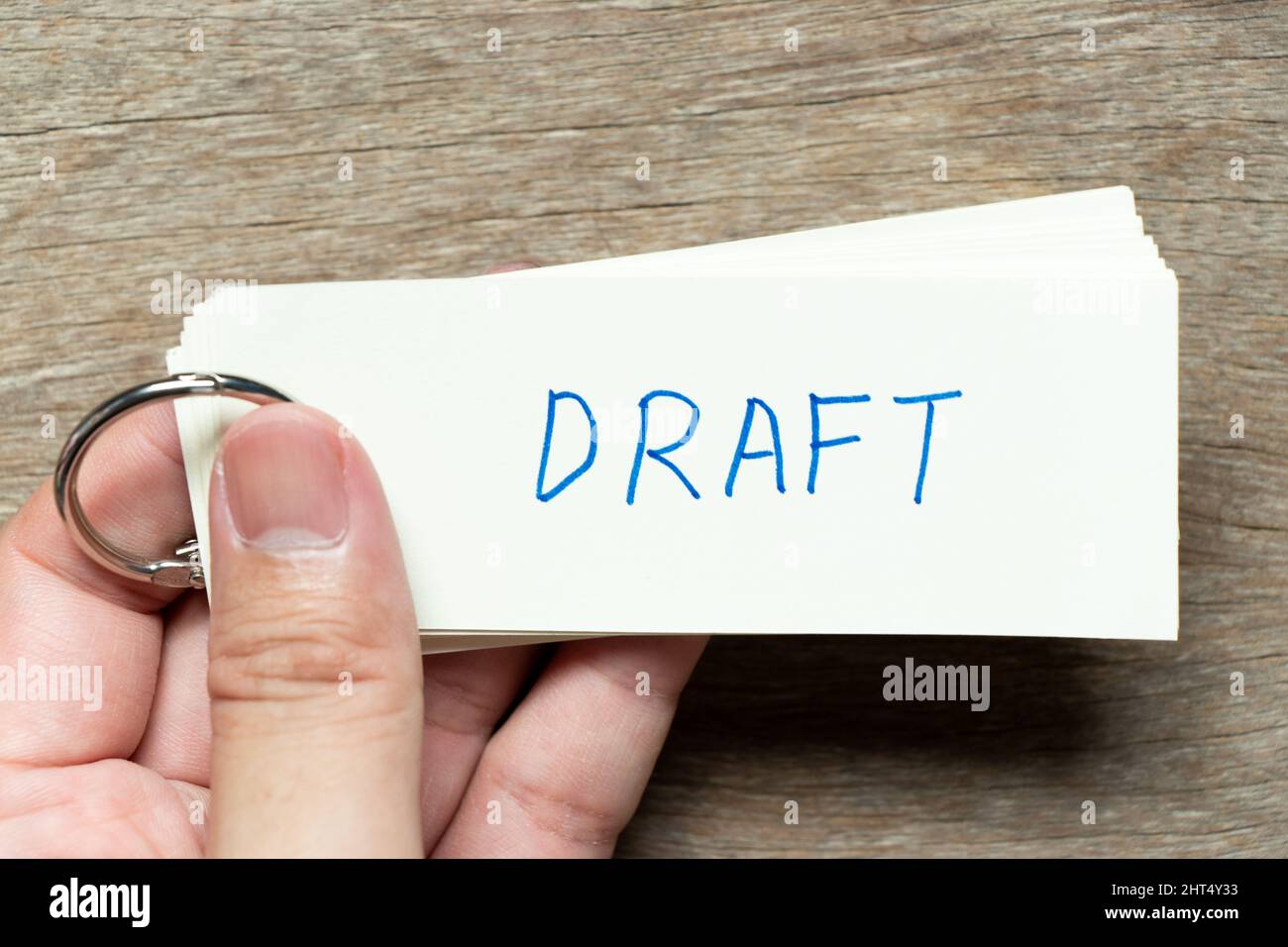 Man hold the flash card with handwriting word draft on wood background ...