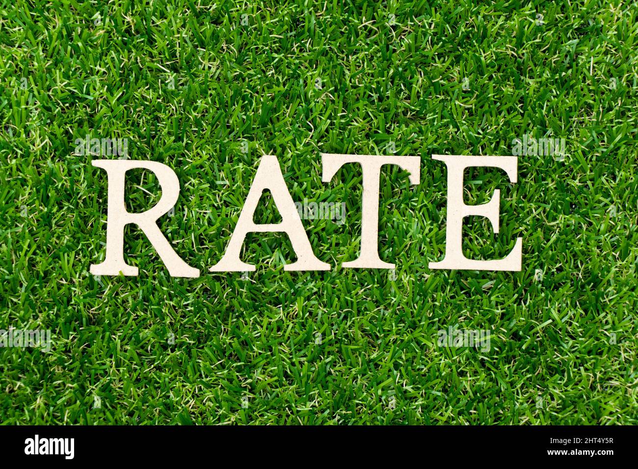 Wood letter in word rate on green grass background Stock Photo - Alamy