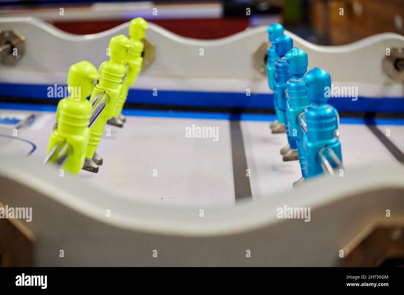 Soft focus of color coordinated men figures on rods of a foosball table ...