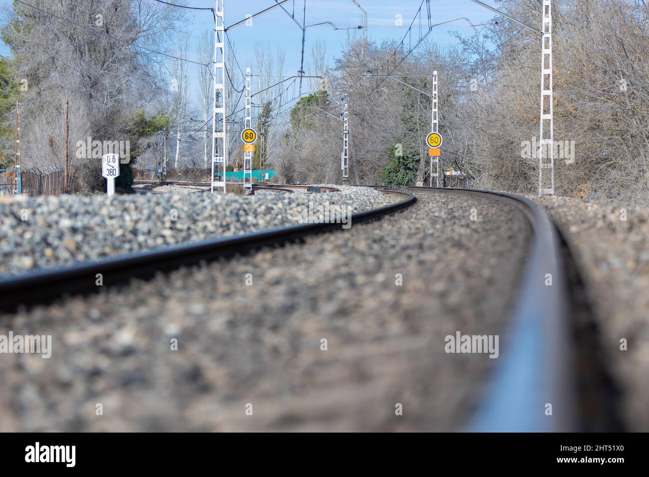 Shallow focus detail of iron railway track with stones under trees and ...
